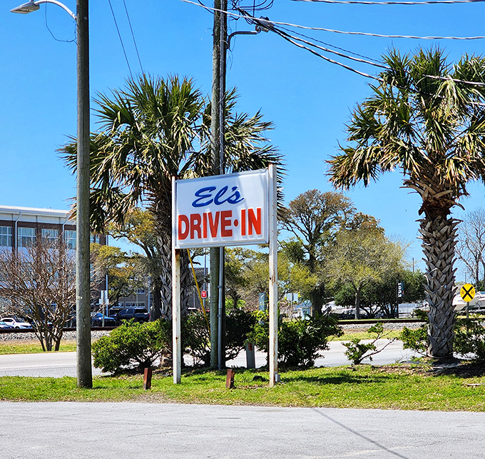 El's roadside sign stands tall among palm trees, a beacon for hungry travelers. Like a lighthouse guiding ships, but for cheeseburgers.