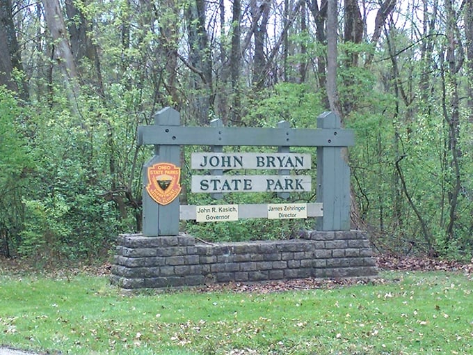 The park entrance sign stands as a humble gatekeeper between everyday life and the natural sanctuary that awaits beyond.