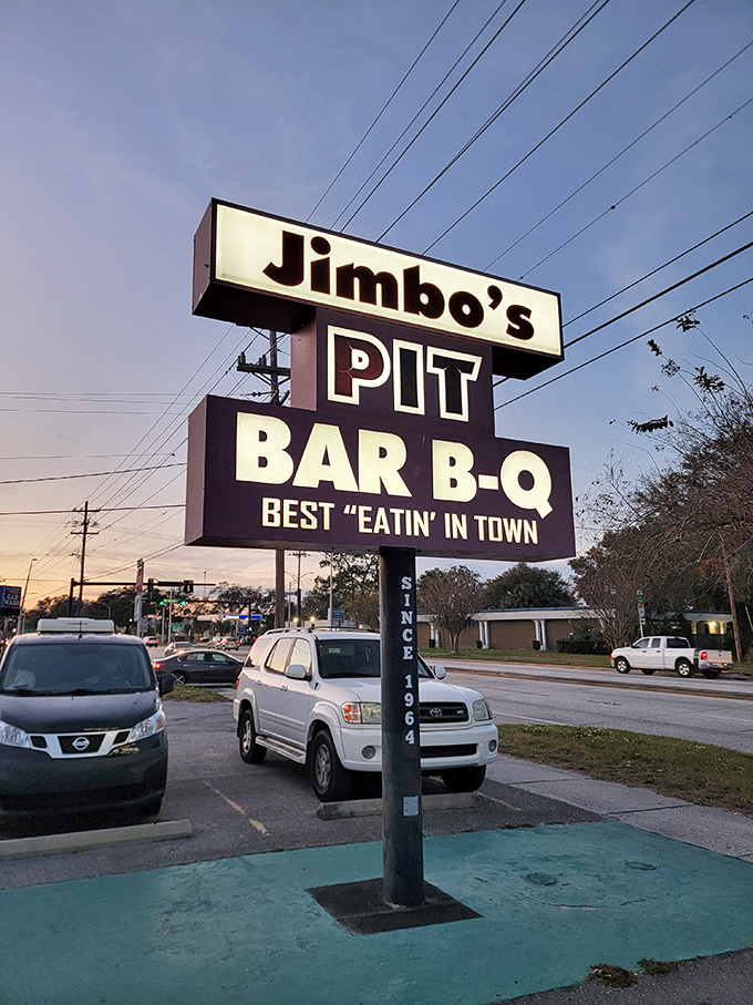 The illuminated sign stands tall against the twilight sky, a beacon for barbecue pilgrims seeking "Best Eatin' in Town" since 1964.