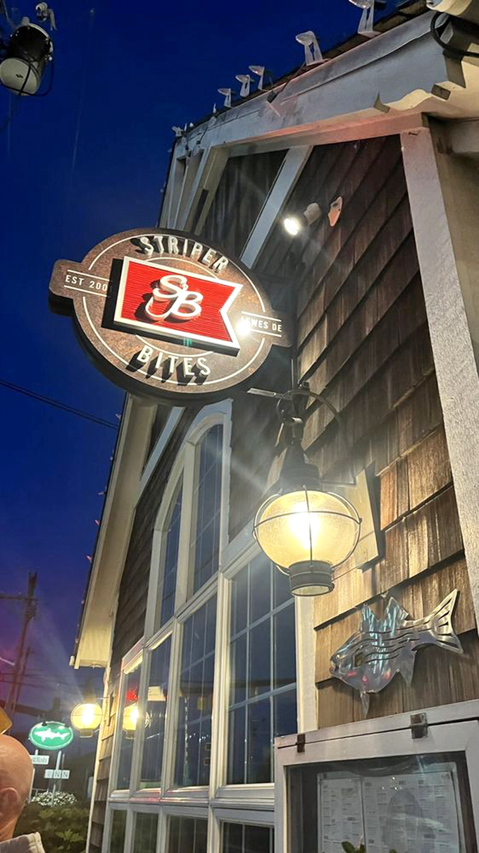 As evening falls, the Striper Bites sign glows like a lighthouse beacon guiding hungry travelers to seafood salvation.