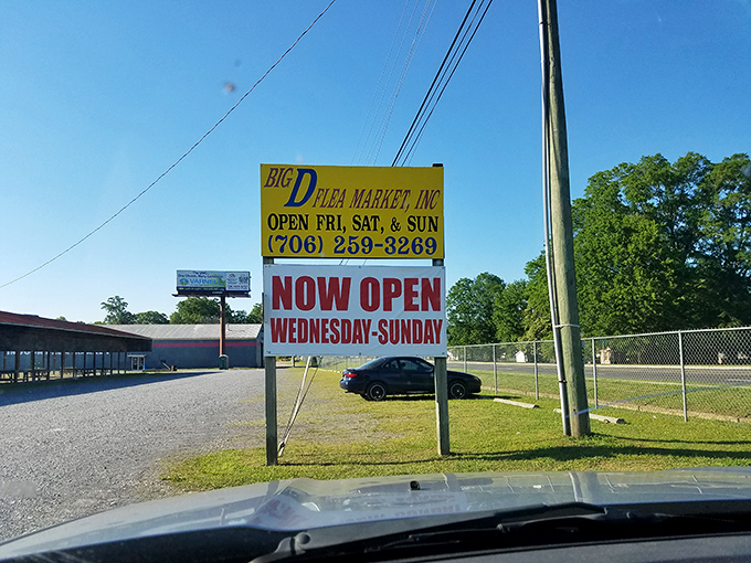 The yellow sign stands like a beacon of bargain-hunting hope, announcing the days when treasure awaits those willing to venture off the highway.