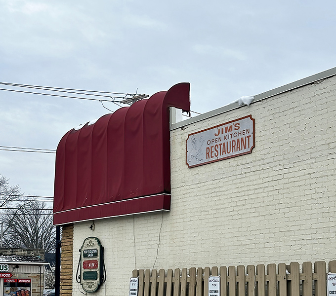 The weathered sign on the white brick exterior tells you everything and nothing&mdash;this isn't just Jim's Open Kitchen, it's a community institution serving memories with every meal. 