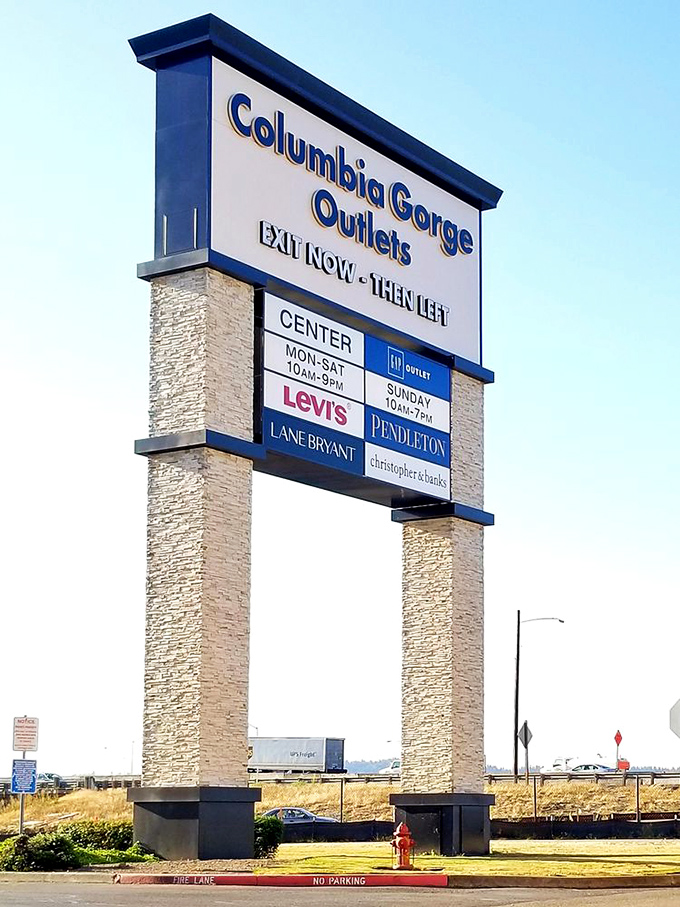 The iconic Columbia Gorge Outlets sign stands tall, beckoning bargain hunters like a retail lighthouse guiding ships to shore.