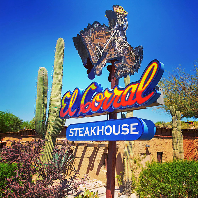 The iconic El Corral sign stands tall against Arizona's blue sky, flanked by saguaro sentinels. Like a neon lighthouse guiding hungry travelers to beefy shores.