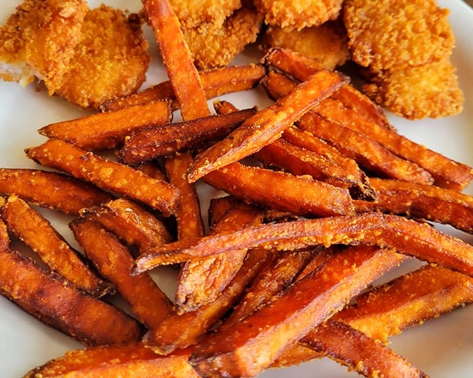 Sweet potato fries with the perfect crisp-to-soft ratio, alongside what appears to be chicken&mdash;the dynamic duo of comfort food superheroes.