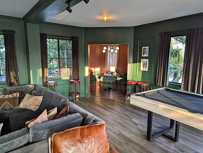 This game room's rich green walls and shuffleboard table create the perfect space for friendly competition&mdash;medieval knights probably settled disputes similarly, minus the cocktails.