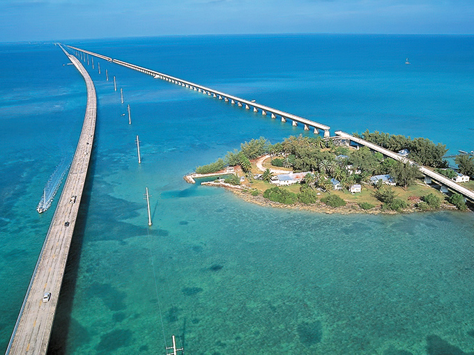 The ultimate bird's-eye view reveals the true artistry of the Seven Mile Bridge&mdash;a graceful concrete arc connecting islands in a sea of impossible blues.