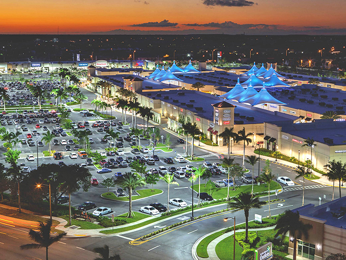 As twilight falls, Tanger transforms into a glittering retail constellation, with blue-lit canopies creating a shopping galaxy under Florida stars.