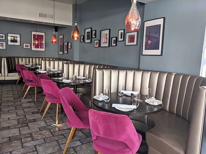 Cream-colored booths and magenta chairs create intimate dining nooks, while pendant lights cast a warm glow that makes everyone look like they've just returned from vacation.