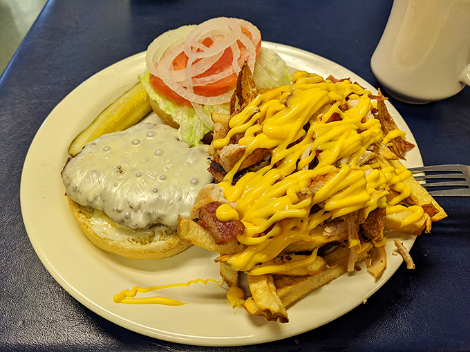 A burger that's dressed for success, accompanied by cheese-draped fries that are clearly not trying to be part of anyone's diet plan.