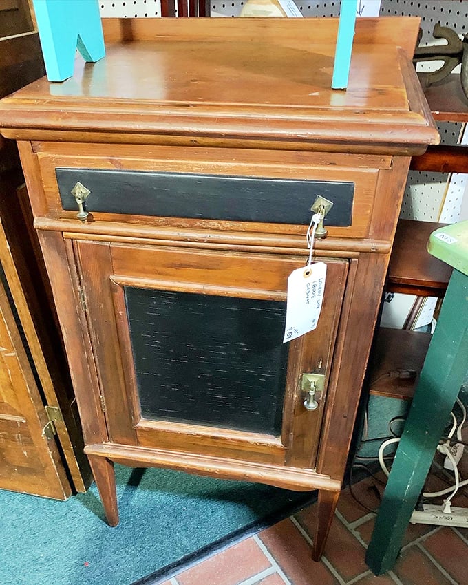 This wooden cabinet with its dark glass panel once held someone's treasures. Now it waits for a new home and a second chance at usefulness.