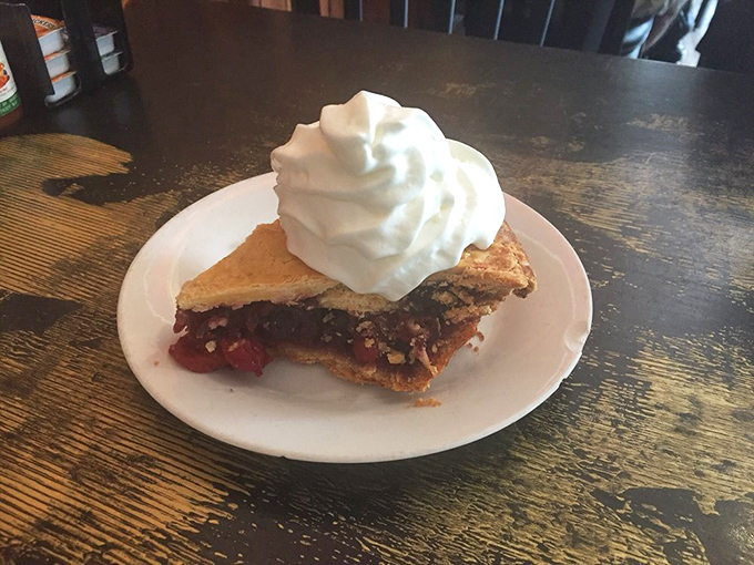 A slice of cherry pie topped with a cloud of whipped cream that makes you wonder why anyone bothers with birthday cake.
