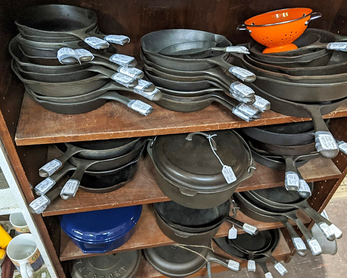 Cast iron heaven! That bright orange colander pops among the seasoned skillets like a cheerful reminder of kitchen gatherings past.
