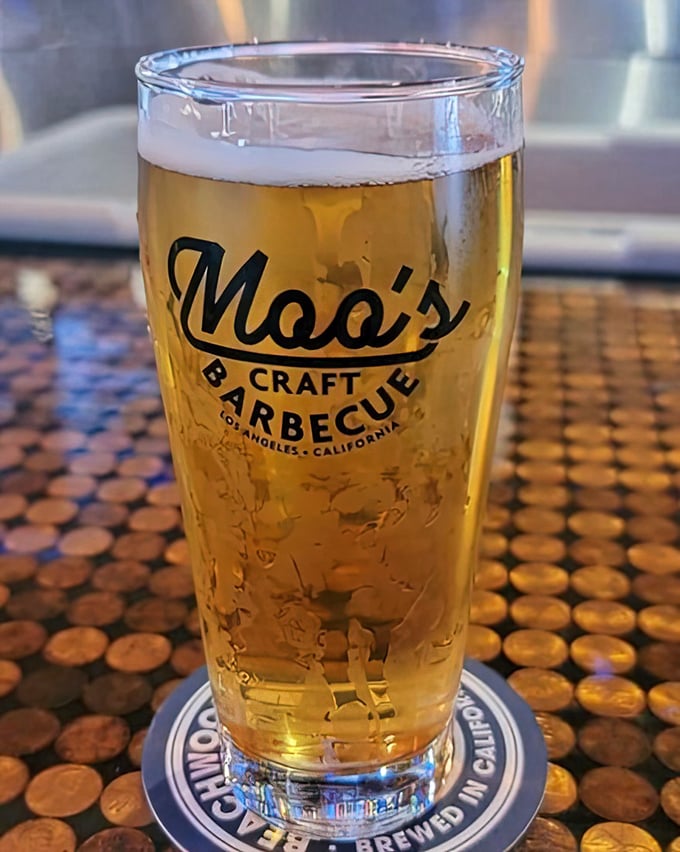 The perfect companion to smoked meats. A golden craft beer in Moo's branded glass, sitting atop a penny-tiled bar that invites lingering.