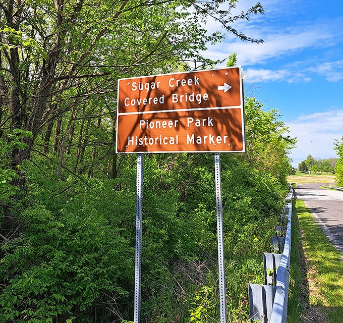 Orange signage stands as the modern town crier, pointing travelers toward a landmark that predates GPS by more than a century.