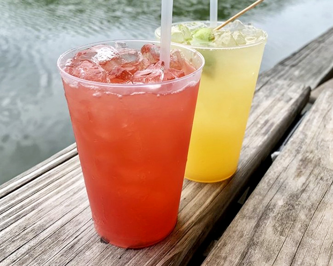 Tropical cocktails in sunset colors taste like liquid vacation while you watch real boats drift past your table.