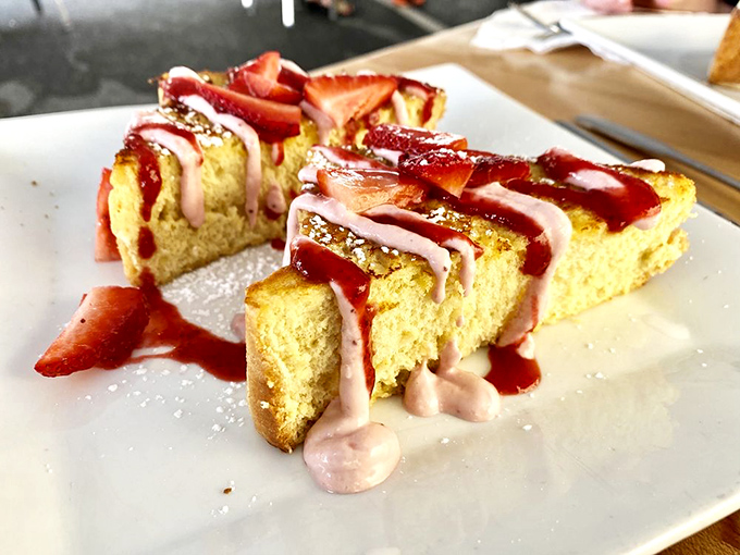 French toast living its best life. Golden perfection adorned with strawberry sauce and cream that transforms bread into a breakfast masterpiece.