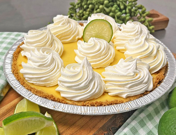 The key lime pie in all its glory&mdash;sunshine-yellow filling, cloud-like whipped cream peaks, and that lime slice winking at you like it knows something.