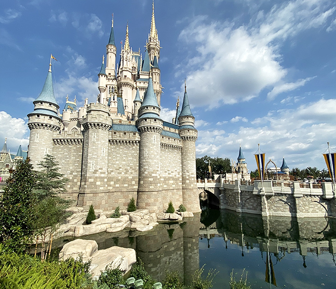 The castle's stone foundation seems to emerge organically from the water, a masterclass in theme park design that blends fantasy with engineering precision.