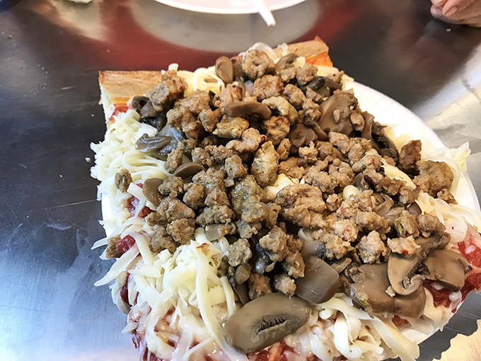 A close-up of pizza perfection &ndash; sausage, mushrooms, and that signature cold cheese creating a topographical map of flavor that needs no explanation.