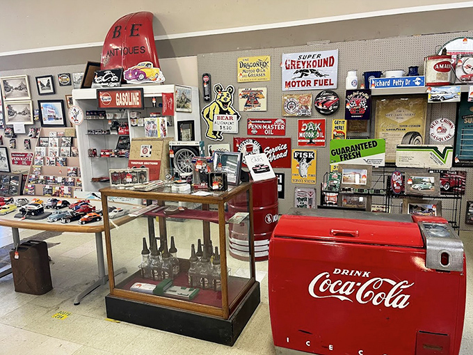 Automotive nostalgia corner with that classic Coca-Cola cooler stealing the show. Remember when gas stations gave away glasses with fill-ups and road trips meant paper maps?