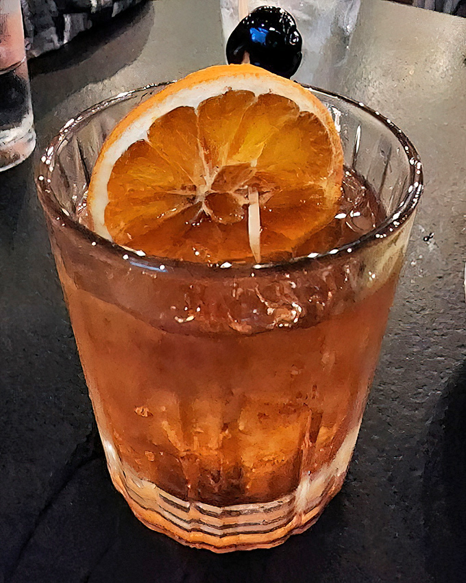 An Old Fashioned with a proper orange slice&mdash;cocktail simplicity at its finest. Amber liquid catching light like liquid nostalgia.