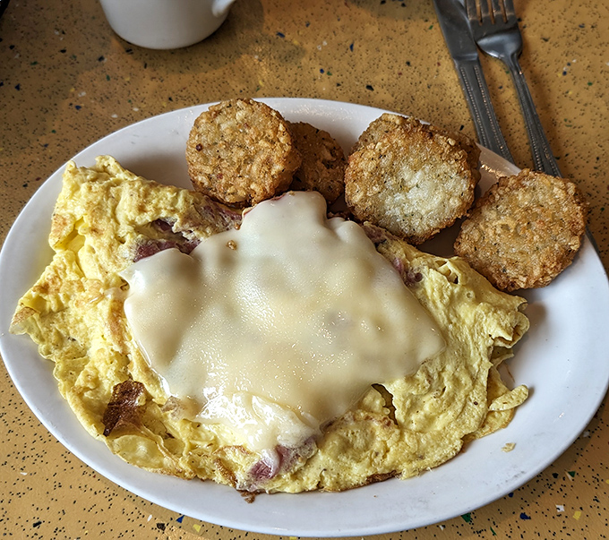 An omelet draped in melted cheese like a cozy blanket, with crispy hash browns standing guard against any possibility of leaving hungry.