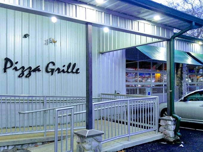 Evening transforms The Pizza Grille's exterior into an inviting beacon of culinary promise, with illuminated signage that practically whispers, "Yes, we're still open. Come on in."