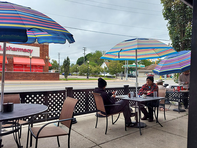 Colorful umbrellas transform sidewalk dining into a mini vacation, proving paradise sometimes comes with hash browns included.