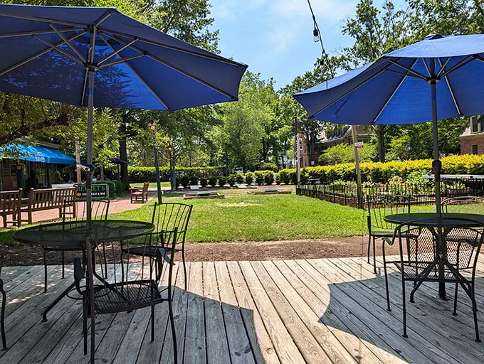 Blue umbrellas create islands of shade on the wooden deck, where summer afternoons stretch lazily into evening over plates of seafood and cold drinks.