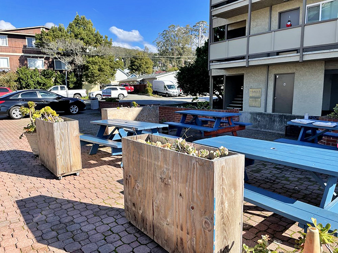 Outdoor seating with blue picnic tables creates the perfect casual atmosphere for enjoying serious barbecue with a side of fresh coastal air.
