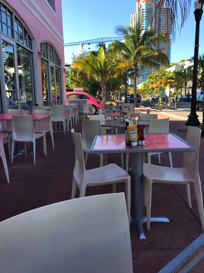 Outdoor seating where Miami's perfect weather becomes the final ingredient in every meal. Palm trees and pink walls frame a quintessential South Beach moment.