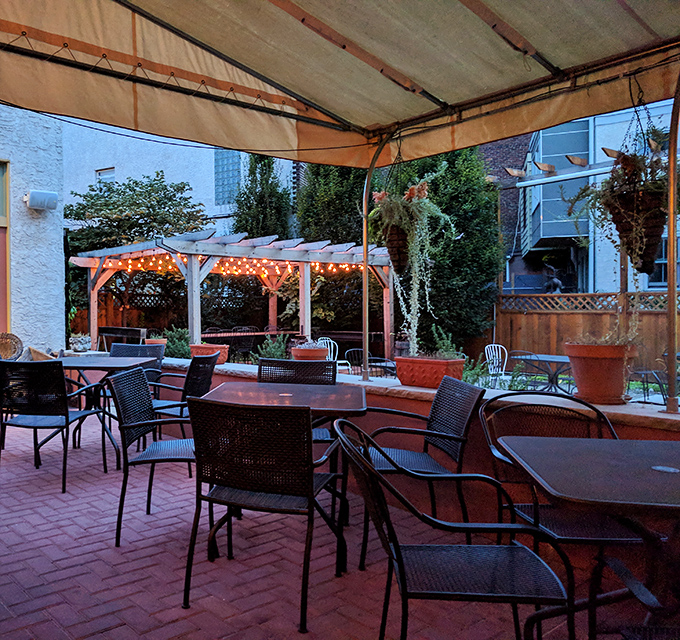 As twilight falls, the patio transforms into an enchanted garden. String lights twinkle above empty tables waiting for tomorrow's stories to unfold.