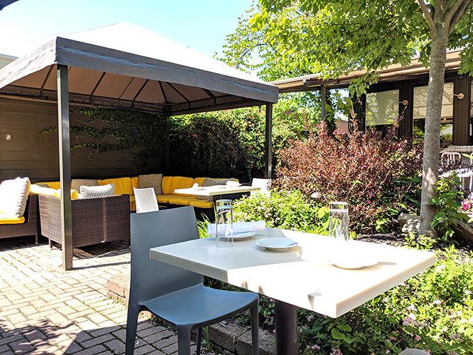 The secluded patio offers an urban oasis where summer meals unfold beneath dappled sunlight, surrounded by lush greenery and civilized conversation.