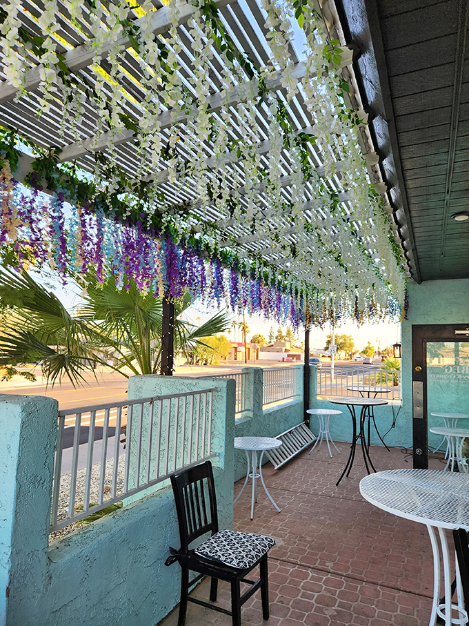 The outdoor seating area blooms with hanging flowers, creating a secret garden vibe that makes waiting for your cinnamon roll even sweeter.