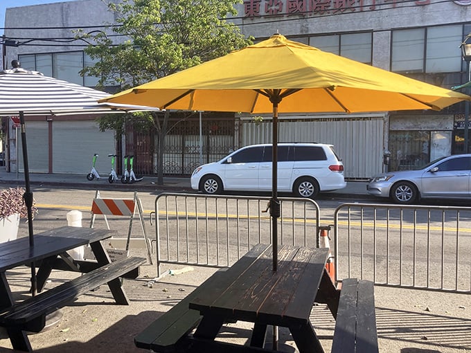 Outdoor seating under yellow umbrellas offers a moment of French Quarter tranquility in the heart of bustling Chinatown.