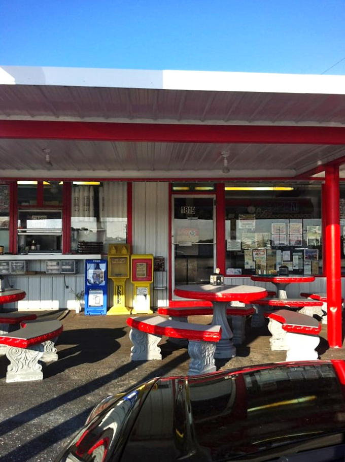 The outdoor seating area&mdash;where Florida sunshine meets American classics. These red tables have supported more happy elbows than an orthopedic clinic.