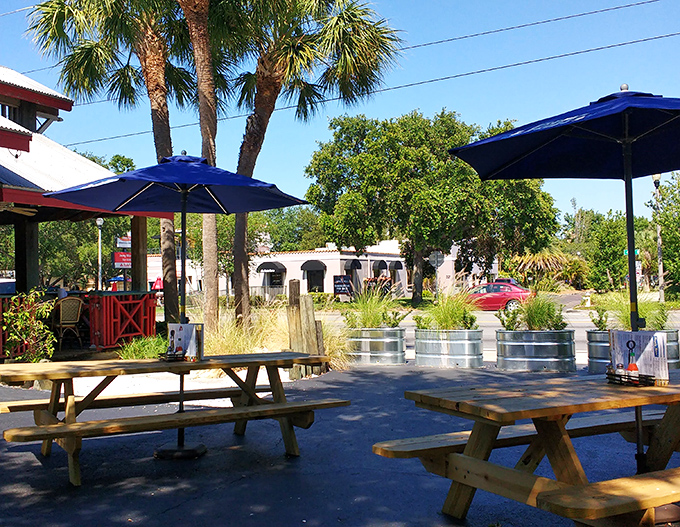 Florida dining as nature intended. These outdoor picnic tables under blue umbrellas aren't just seating&mdash;they're front-row tickets to sunshine and satisfaction.