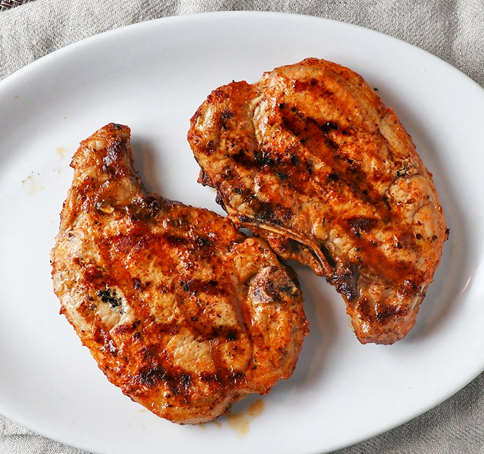 Two perfectly grilled pork chops on a pristine white plate&mdash;minimalist food art that speaks volumes without saying a word.