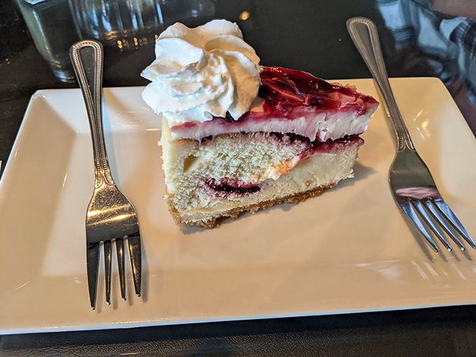 A slice of raspberry cheesecake that makes you wonder if you should skip dinner and just order another piece.