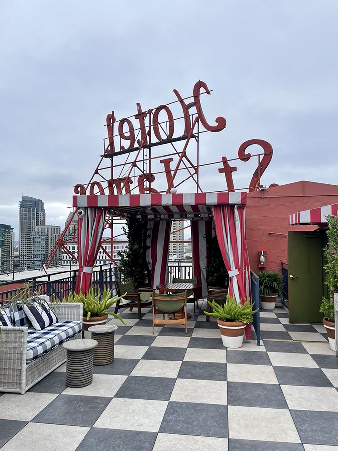 "Hotel" spelled backward on the rooftop creates an Alice-in-Wonderland charm. Red and white striped awning against the San Diego skyline&mdash;whimsy with a view.