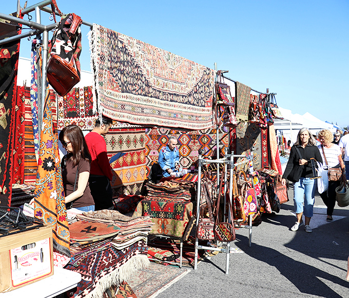 Textile heaven unfolds as shoppers browse handwoven rugs from distant lands&mdash;each one telling stories of ancient patterns and traditions through vibrant threads and intricate designs.