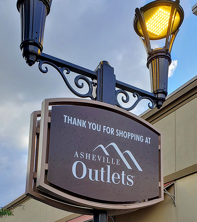 "Thank you for shopping at Asheville Outlets" – a friendly farewell sign illuminated against the Blue Ridge sky.