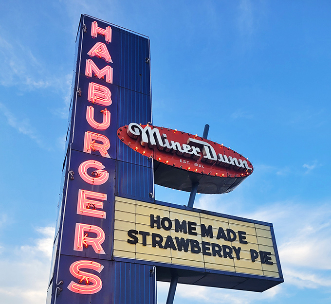 That neon sign isn't just advertising &ndash; it's a lighthouse guiding hungry travelers to a port of hamburger salvation.