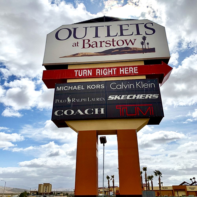 The towering sign stands like a retail lighthouse, guiding weary travelers toward fashion salvation between LA and Vegas.