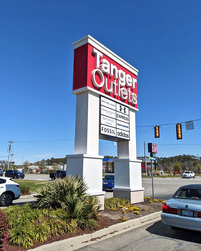 The iconic red sign that serves as a retail lighthouse, guiding bargain hunters safely to shore. Brand names displayed like trophies on this monument to savvy shopping.