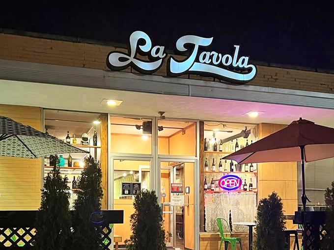As evening falls, La Tavola's sign glows like a beacon for those seeking honest Italian food without pretense or passport requirements.