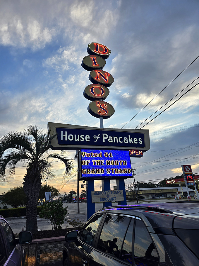 The vertical neon sign stands tall against Carolina skies, a beacon of breakfast hope for travelers and locals alike.