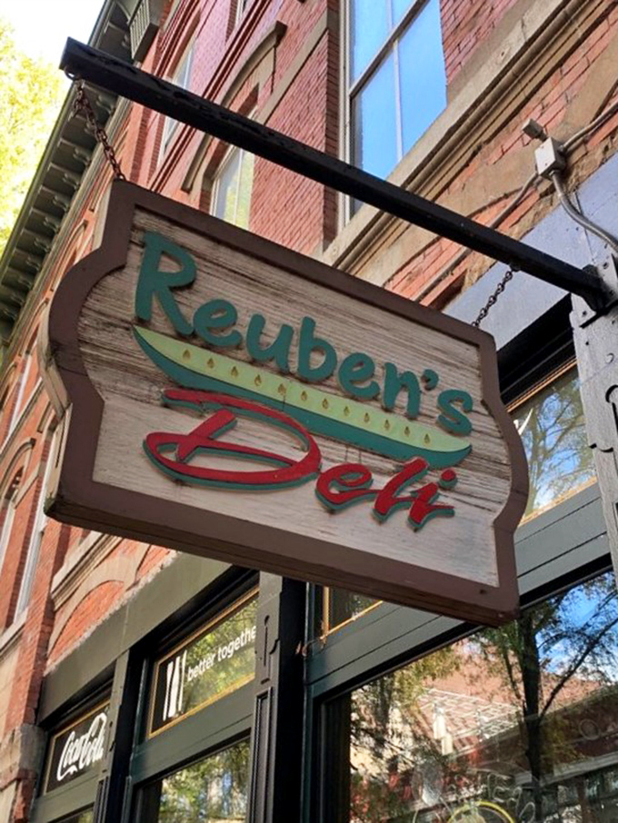 The weathered wooden sign swinging above – a beacon of hope for the hungry and a landmark for sandwich pilgrims.