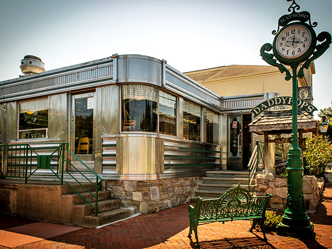 The classic diner exterior gleams in the sunlight like a silver beacon of hope for the hungry, complete with vintage clock and welcoming bench.